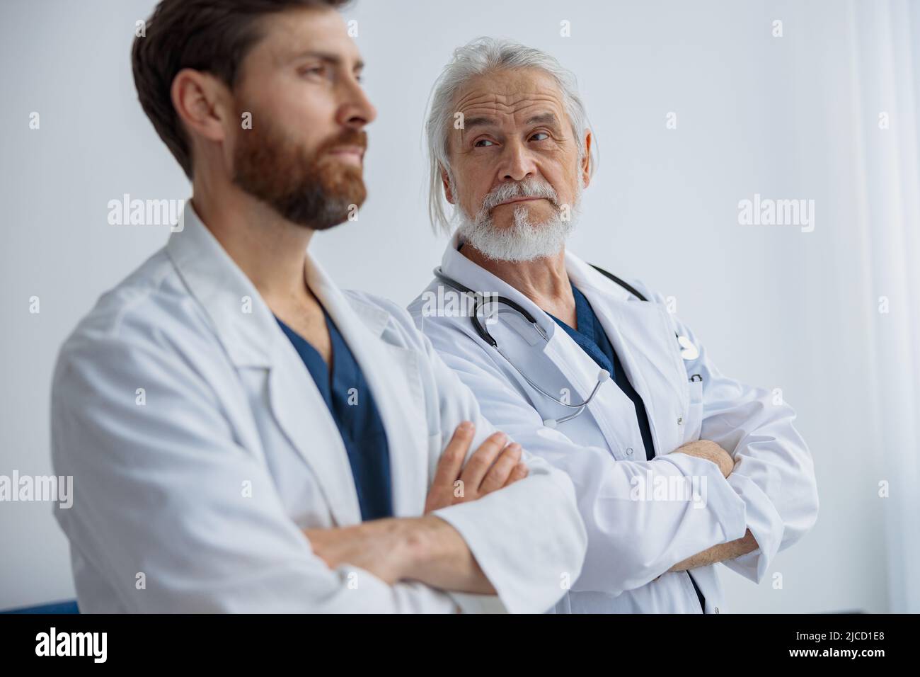 Two professional doctors in uniform standing in hospital with crossing ...