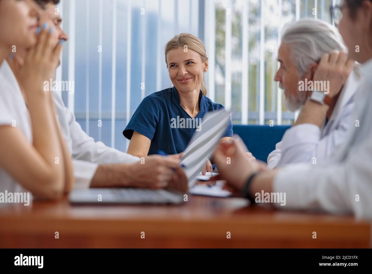 Group of doctors sitting at meeting table in conference room during ...