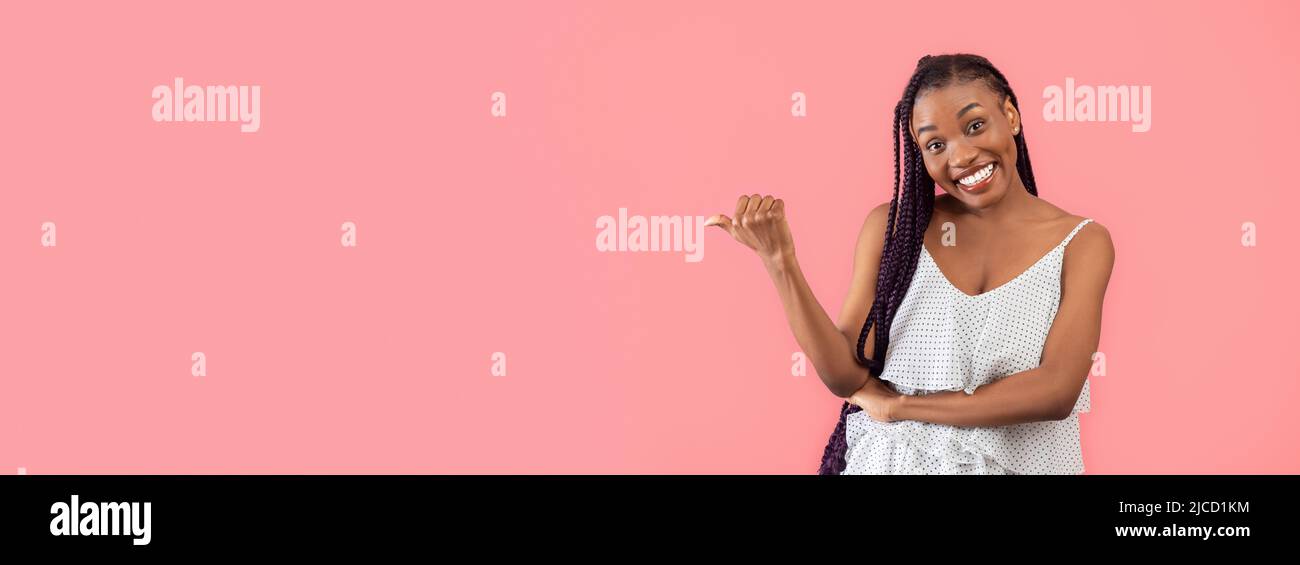 Pretty millennial black woman in trendy summer dress pointing at blank ...