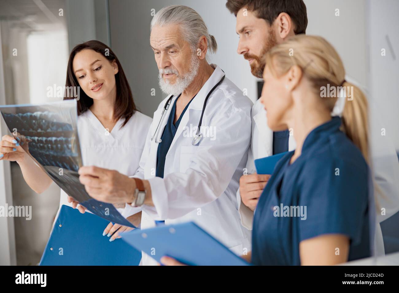 Group of doctors in uniform look and discuss an X-ray or MRI scan of ...