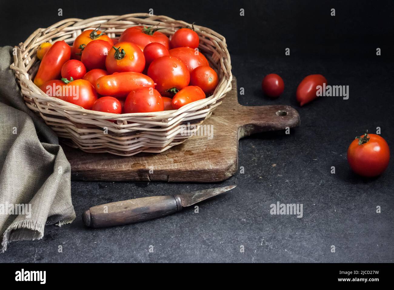 Fresh red tomatoes in whicker basket on black background Stock Photo ...