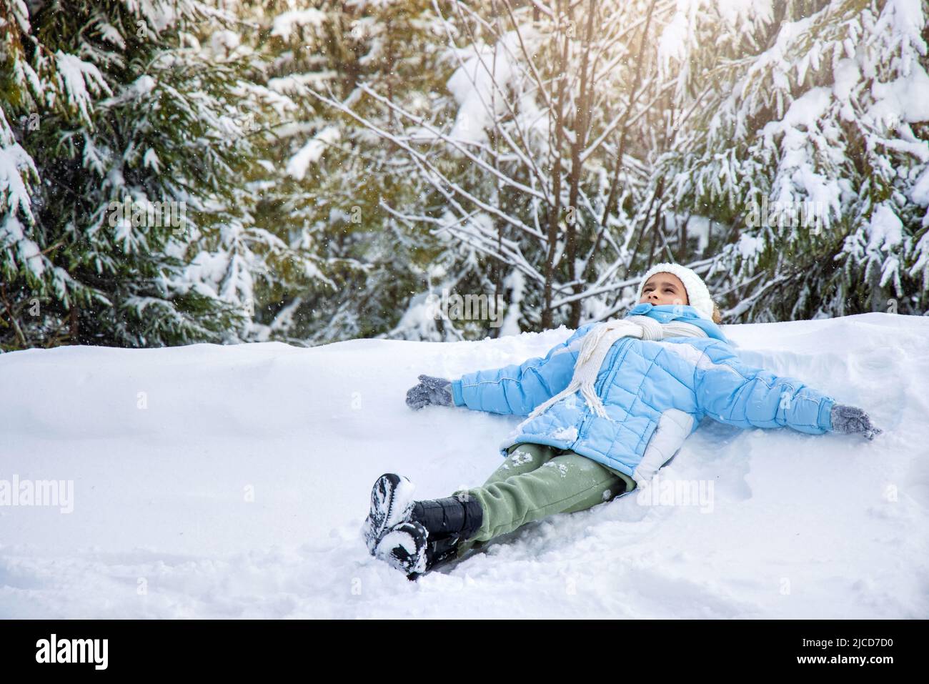 Above view of cute little girl making snow angel in fresh deep snow ...