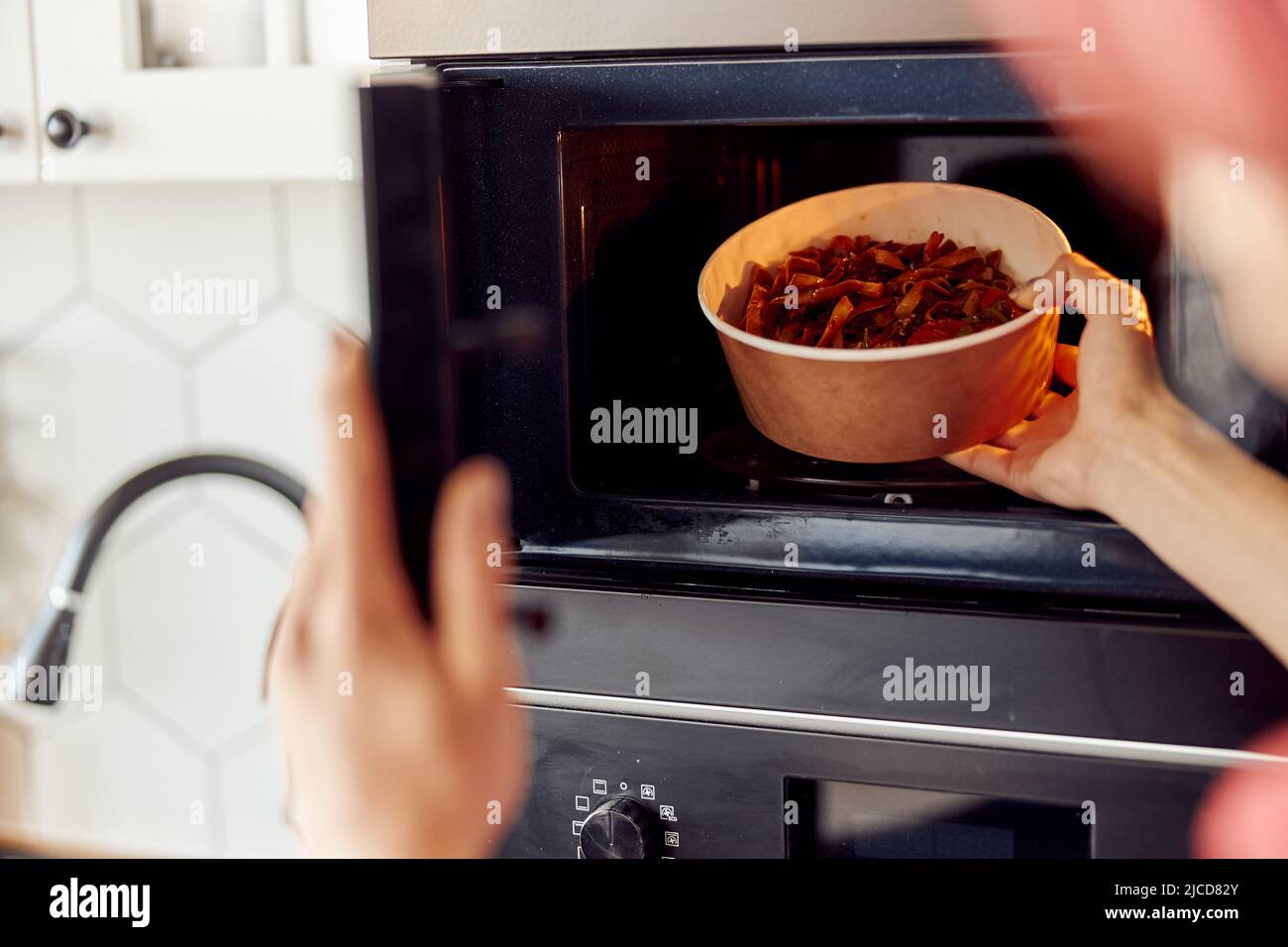 Guy giving foods into the microwave for warm up Stock Photo - Alamy