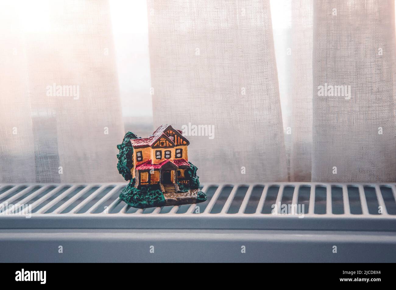 House heating system. House model on a white radiator indoors, space ...