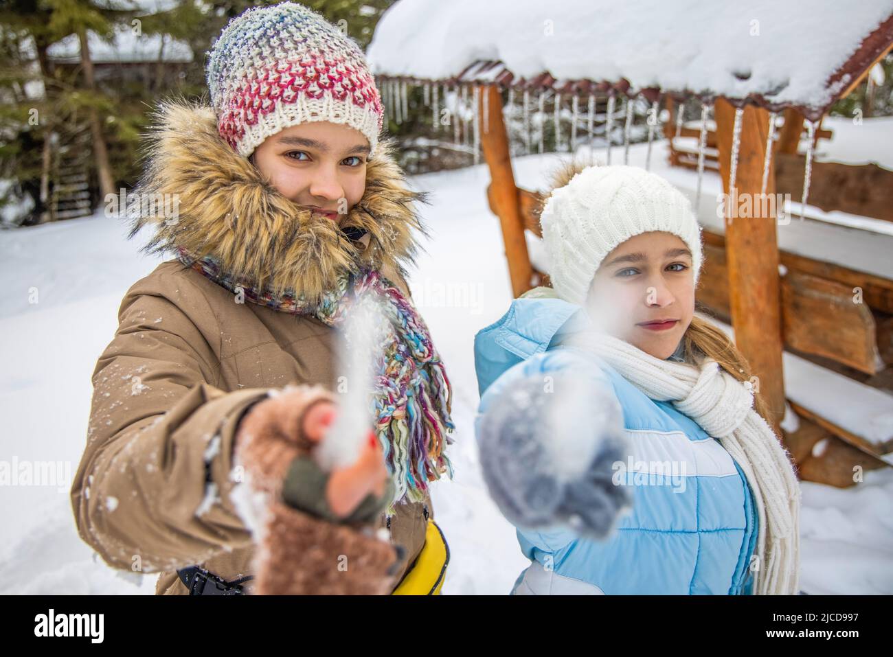 Two funny cheerful friendly girls in warm winter bright clothes poke ...