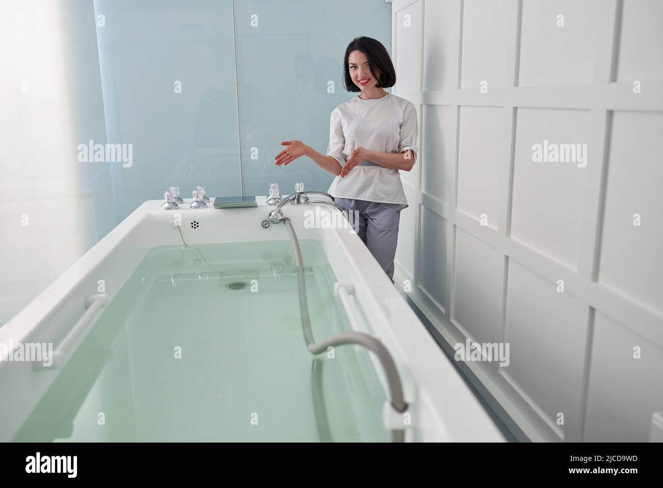 Attractive lady assistant invites to take hydro massage bath in spa ...