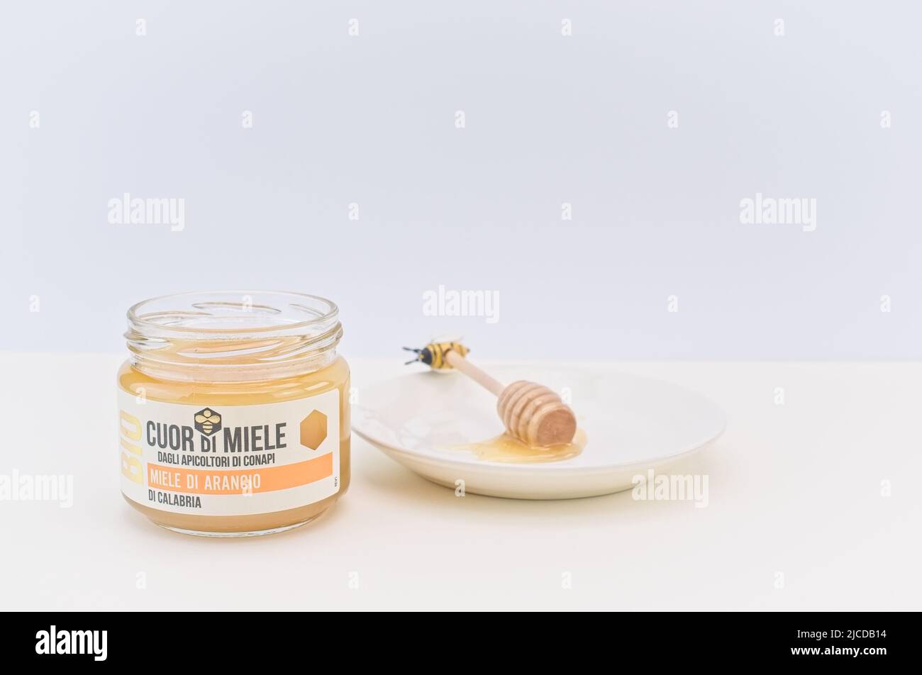 bio organic honey jar with wooden honey dipper and white dessert plate ...