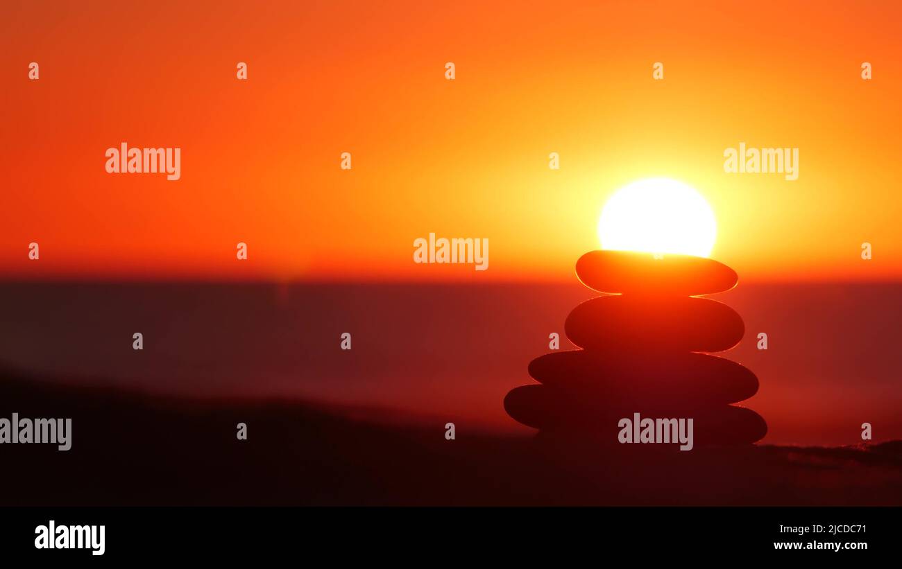 Stack of pebble stones, sandy ocean beach, sunset sky. Rock balancing ...