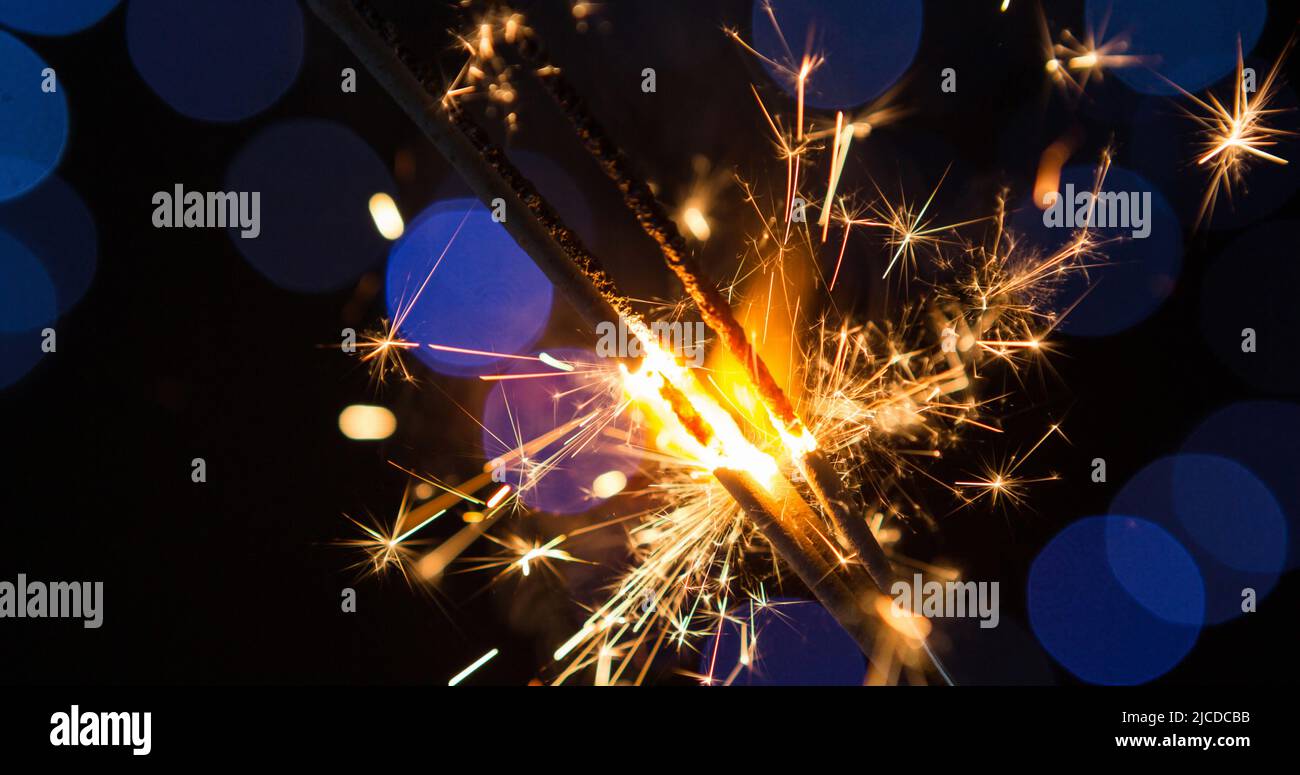 Image of sparklers and blue bokeh lights scrolling on black background ...