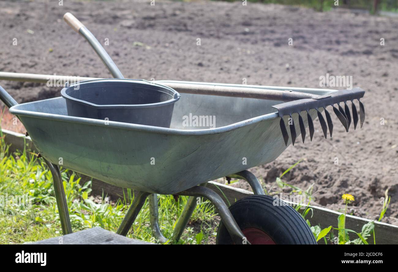 Gray metal garden wheelbarrow with two handles and one wheel. The ...