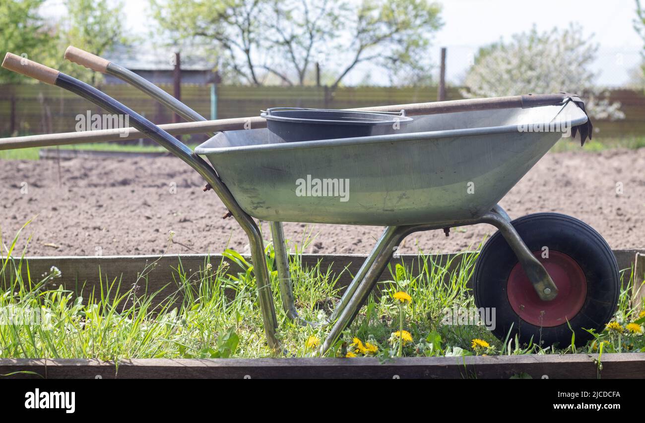 Gray metal garden wheelbarrow with two handles and one wheel. The ...