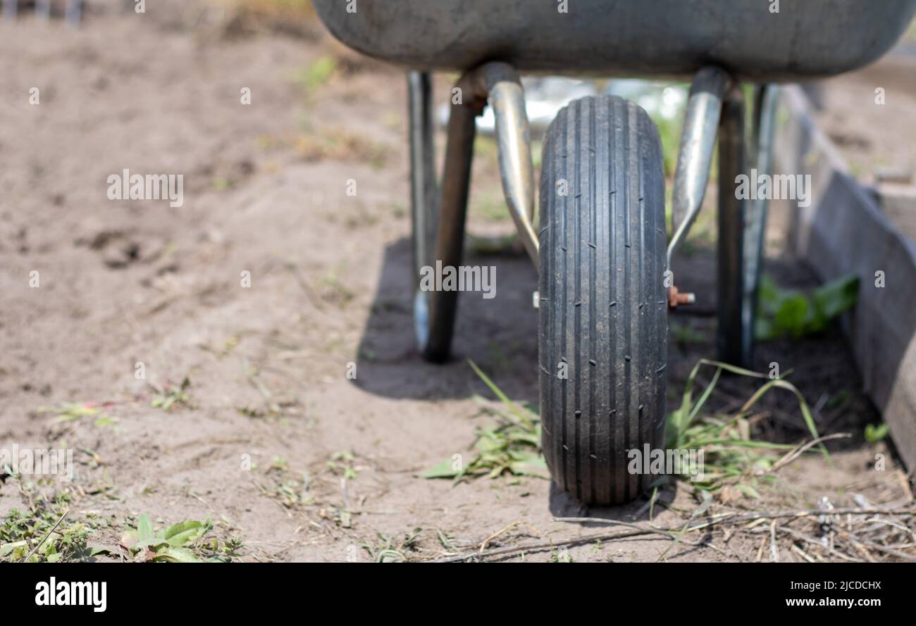 Gray metal garden wheelbarrow with two handles and one wheel. The ...