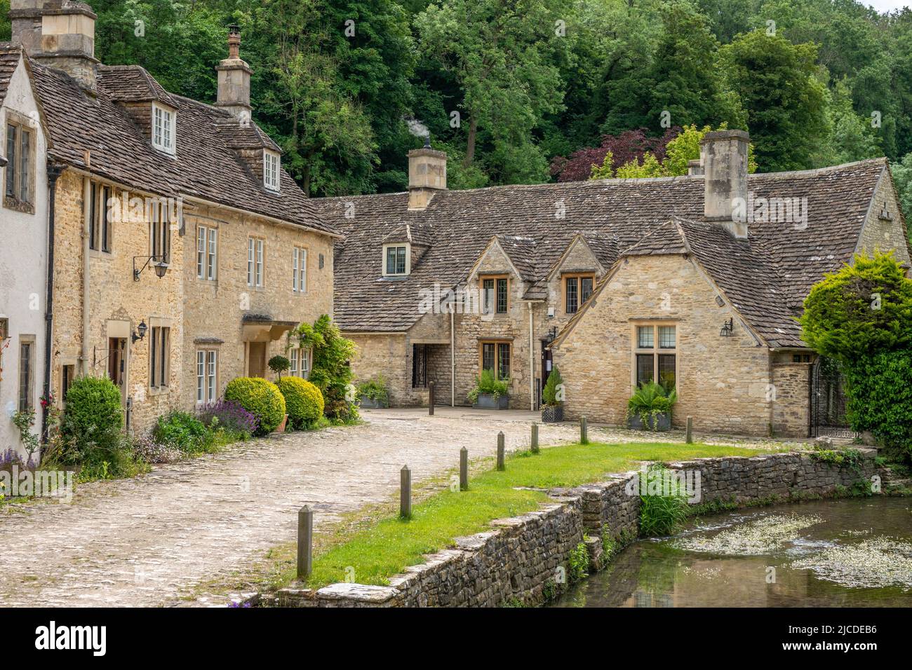 honey coloured Cotswold stone houses and Bybrook river in Castle Combe ...