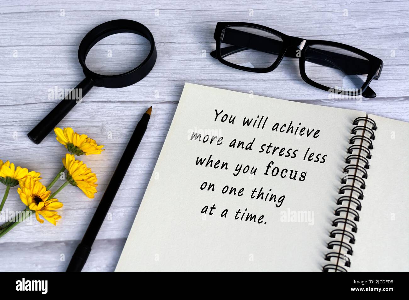 Motivational quote on note book with magnifying glass on white wooden ...