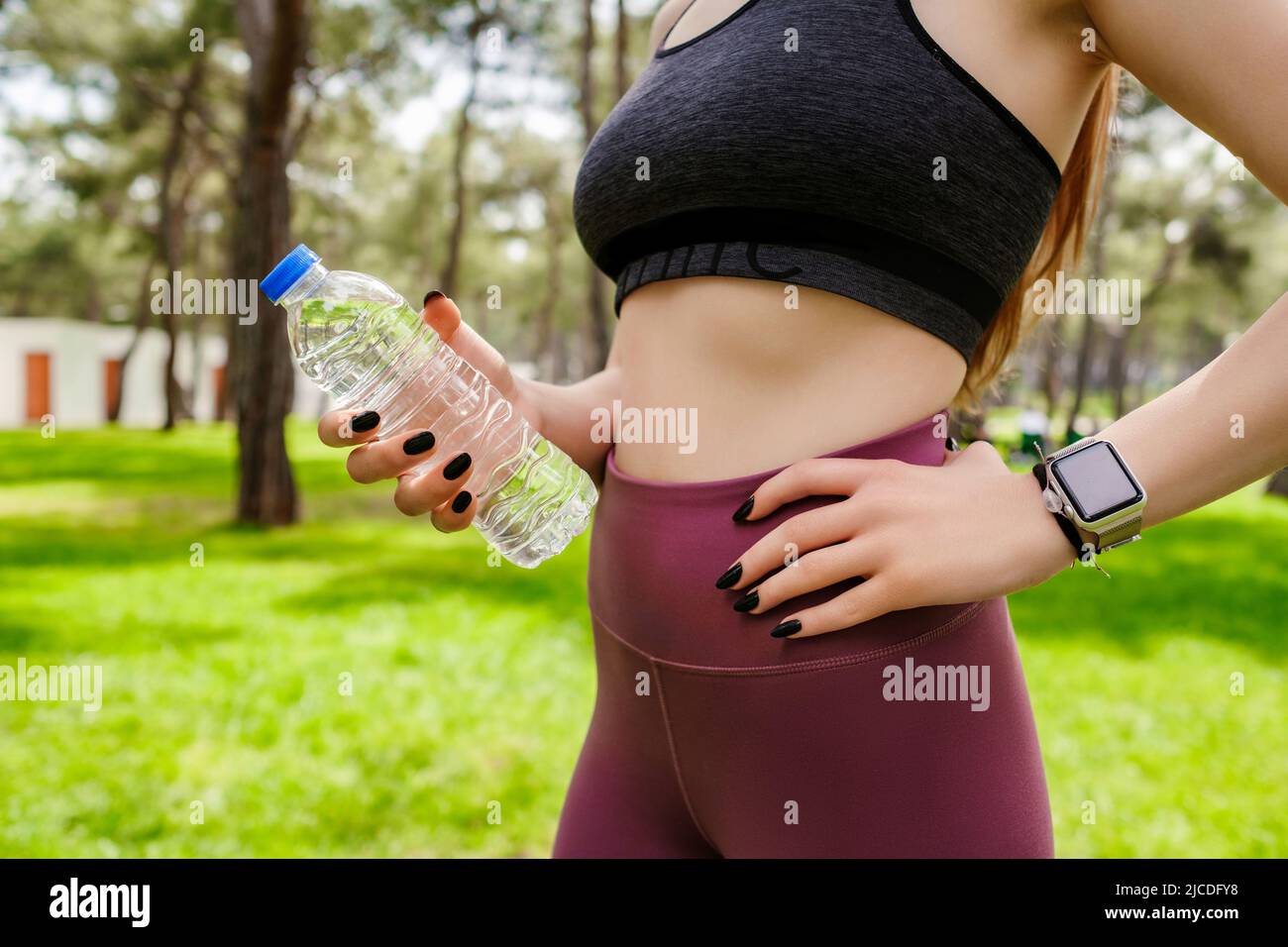 Brunette sportive woman wearing black sports bra standing on city park ...
