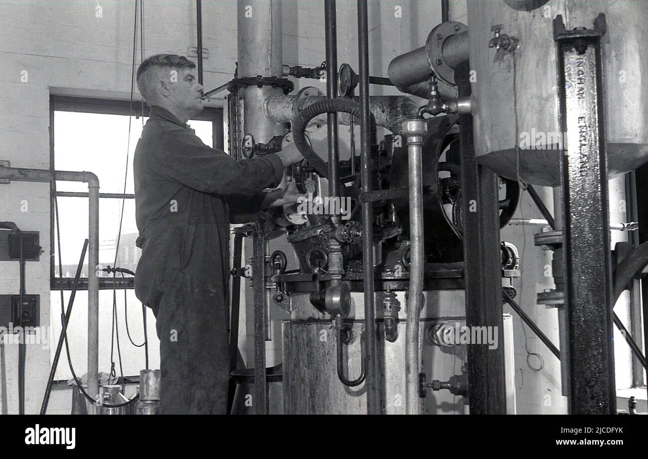 1960s, historical, a male operative in overalls adjusting a wheel valve ...