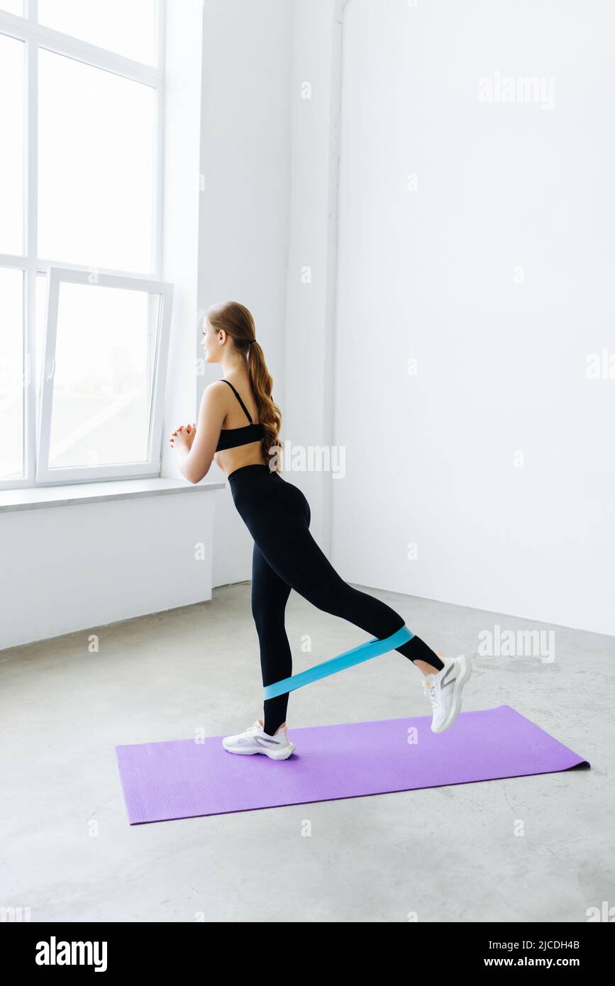 Fitness woman doing exercise for glutes with resistance band on gray ...