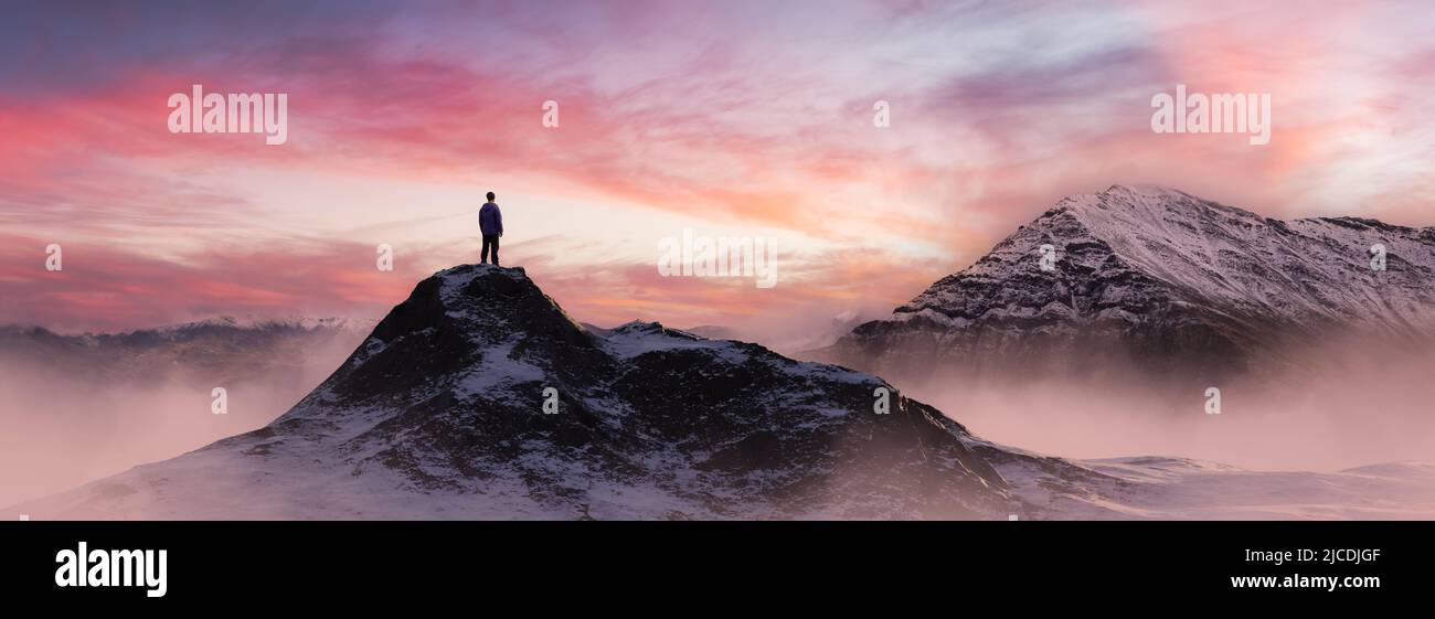 Adventurous Man Hiker standing on top of icy peak with rocky mountains ...