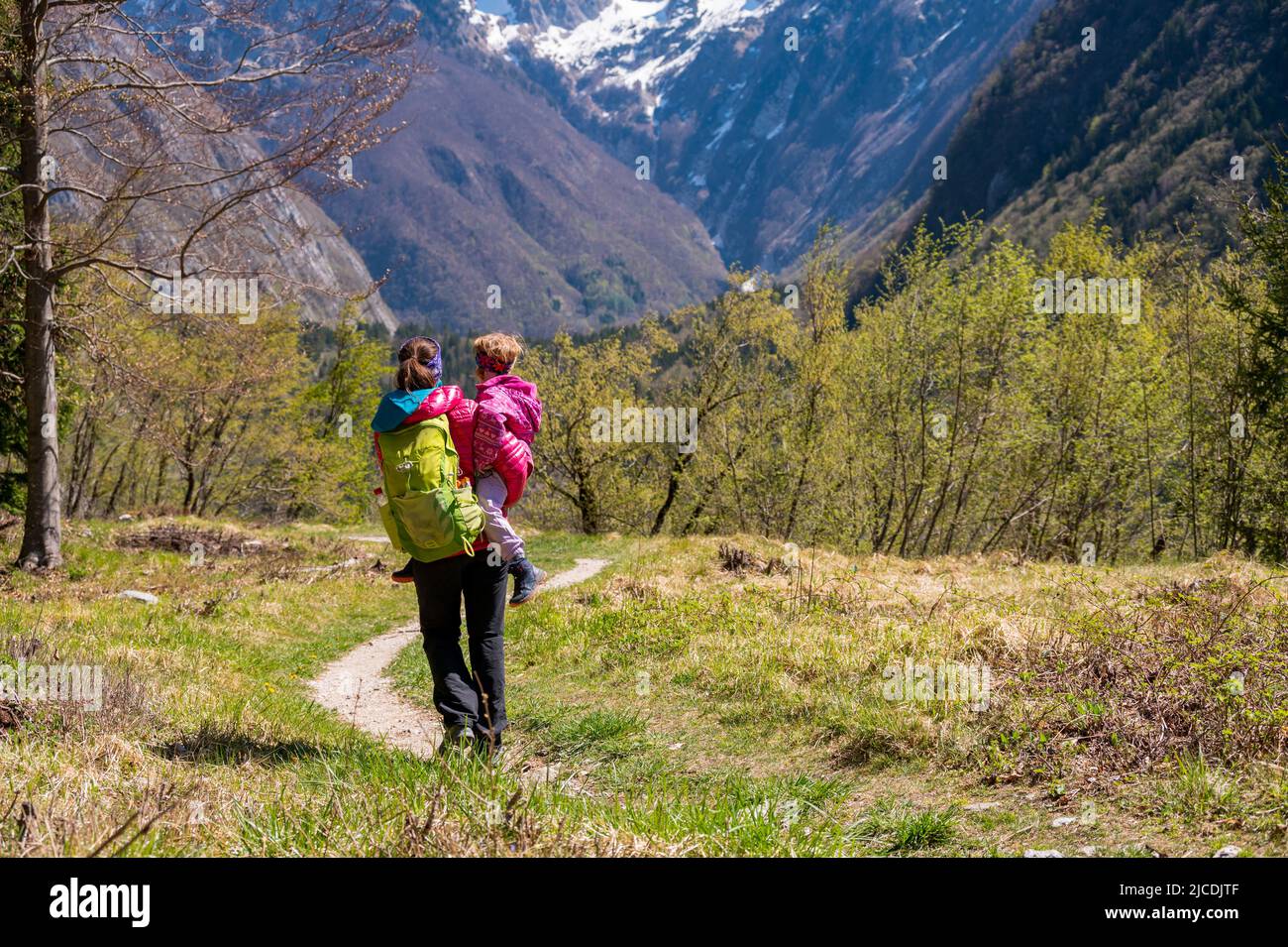 Mother holding his daughter in embrace while walking on forest meadow ...