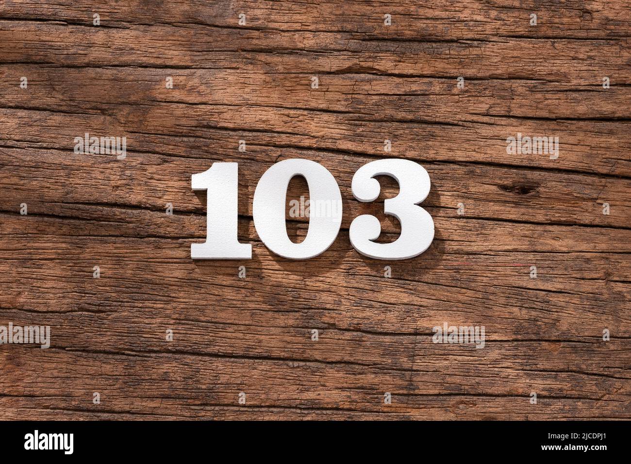 Number 103 - piece on rustic wood background Stock Photo - Alamy