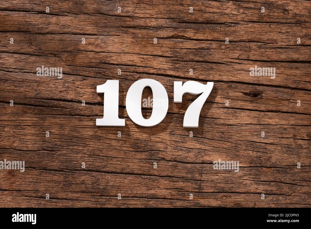 Number 107 - piece on rustic wood background Stock Photo - Alamy
