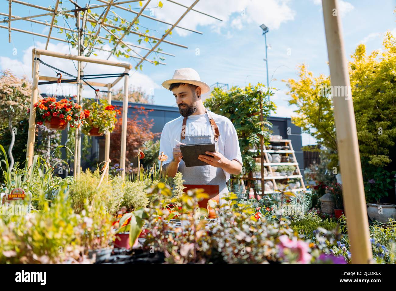 Man worker in garden centre. Using tablet. Gardener Stock Photo - Alamy