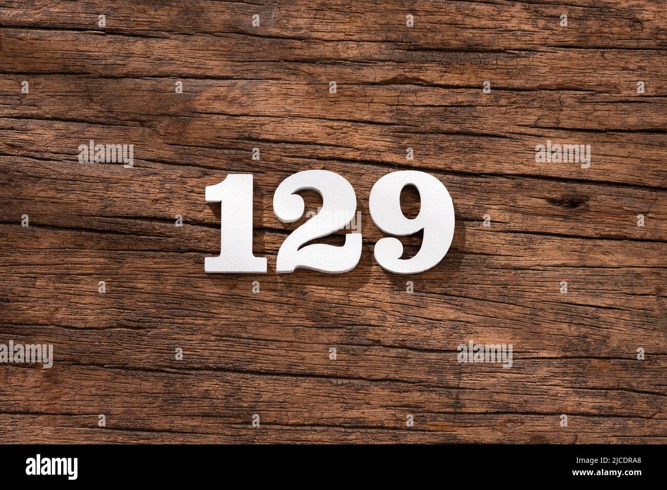 Number 129 - piece on rustic wood background Stock Photo - Alamy