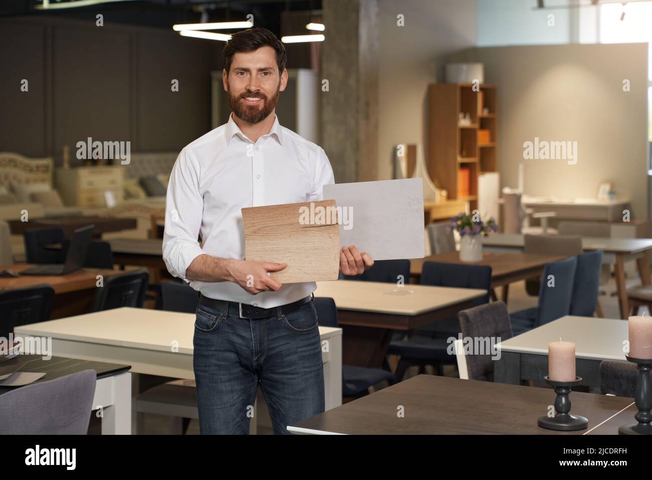 Front view of brunette male with beard standing in furniture store ...