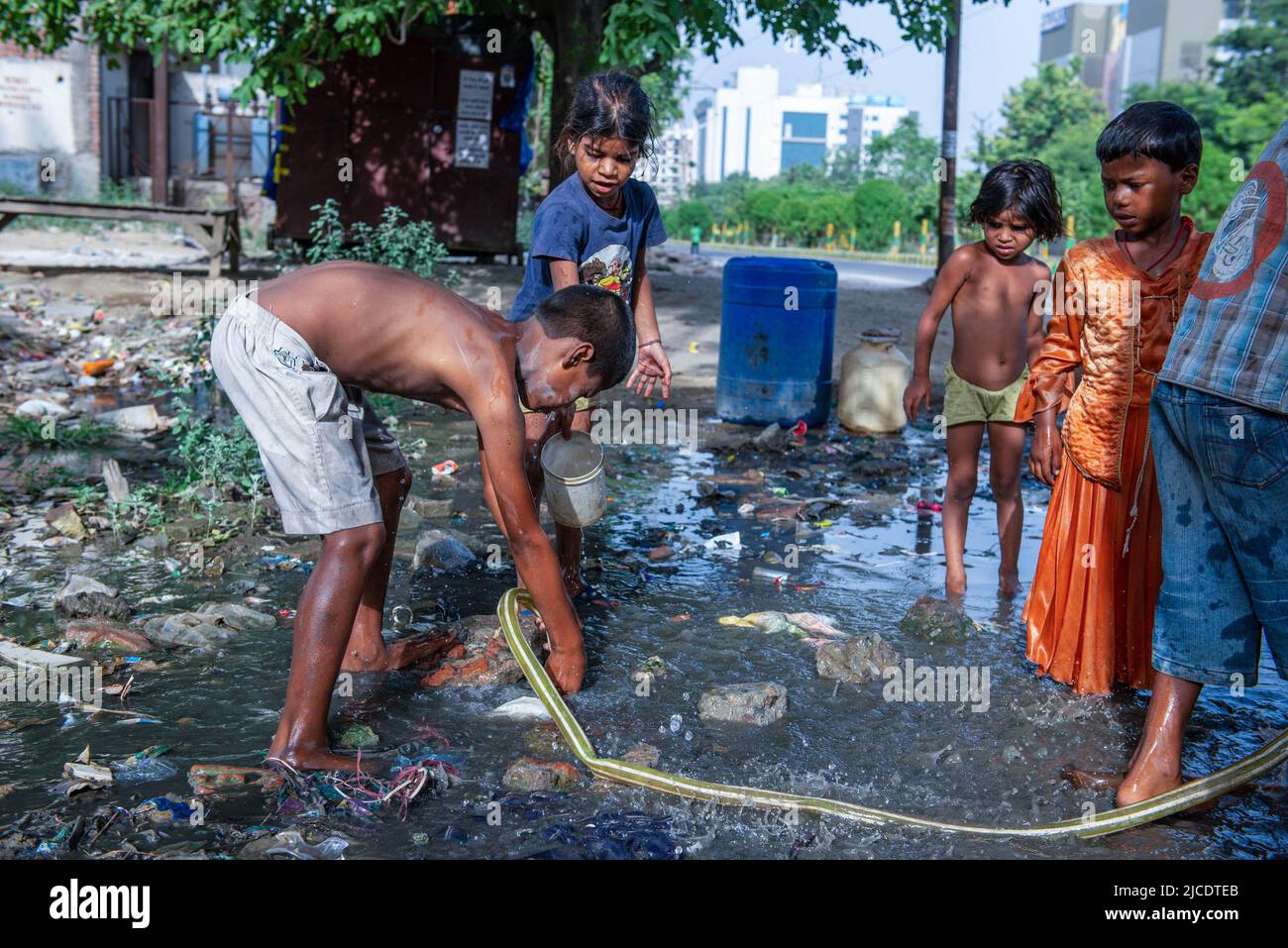 A boy tries to fix a pipe on a water pipeline leakage so as to collect ...