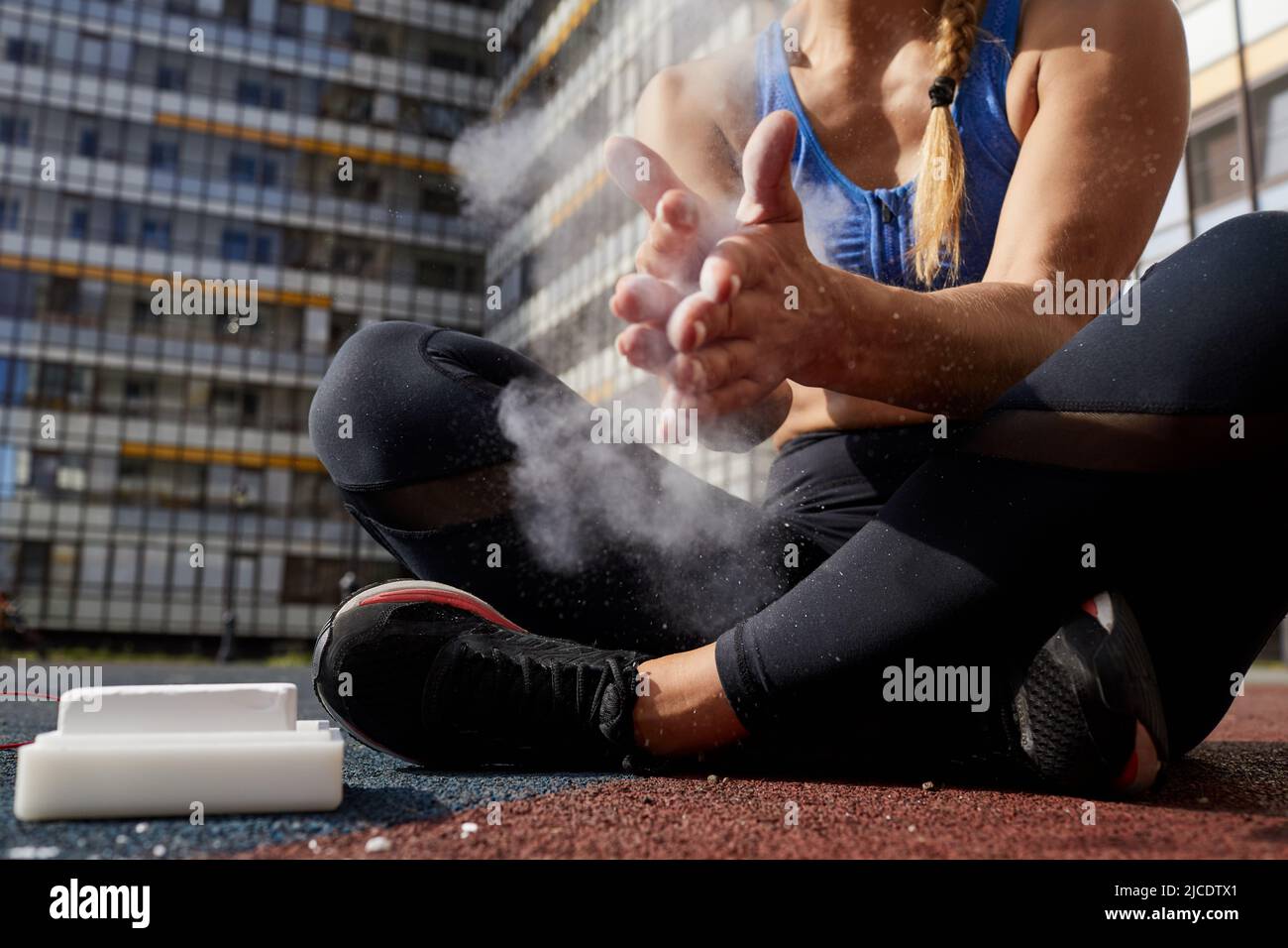 Close-up of unrecognizable woman in leggings sitting with crossed legs ...