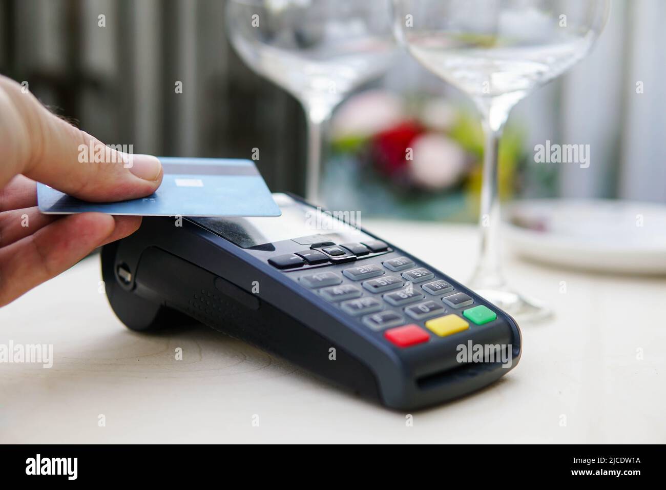 Credit card bank payment terminal near glasses and plates on table in ...