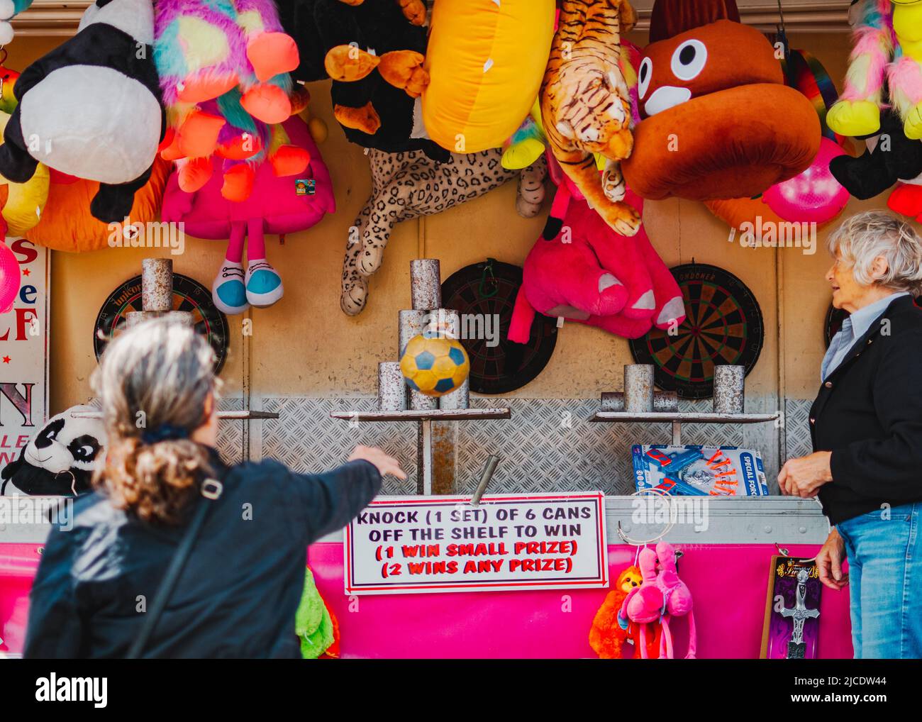 Woman wearing a black coat throwing a ball at tin cans at the Morpeth ...