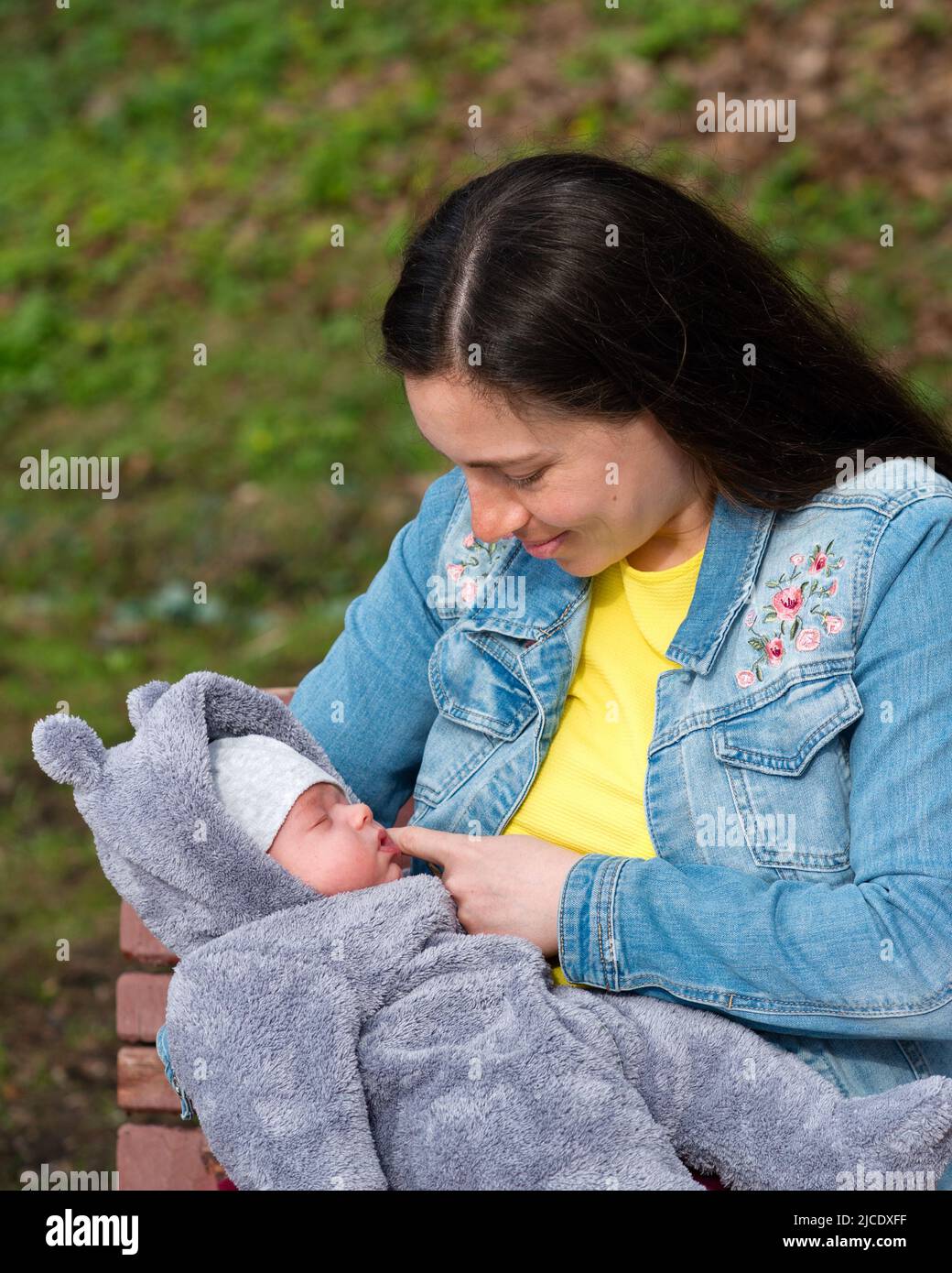 Mom with Newborn Son on Her Arms Spend Time Together in Spring Park ...