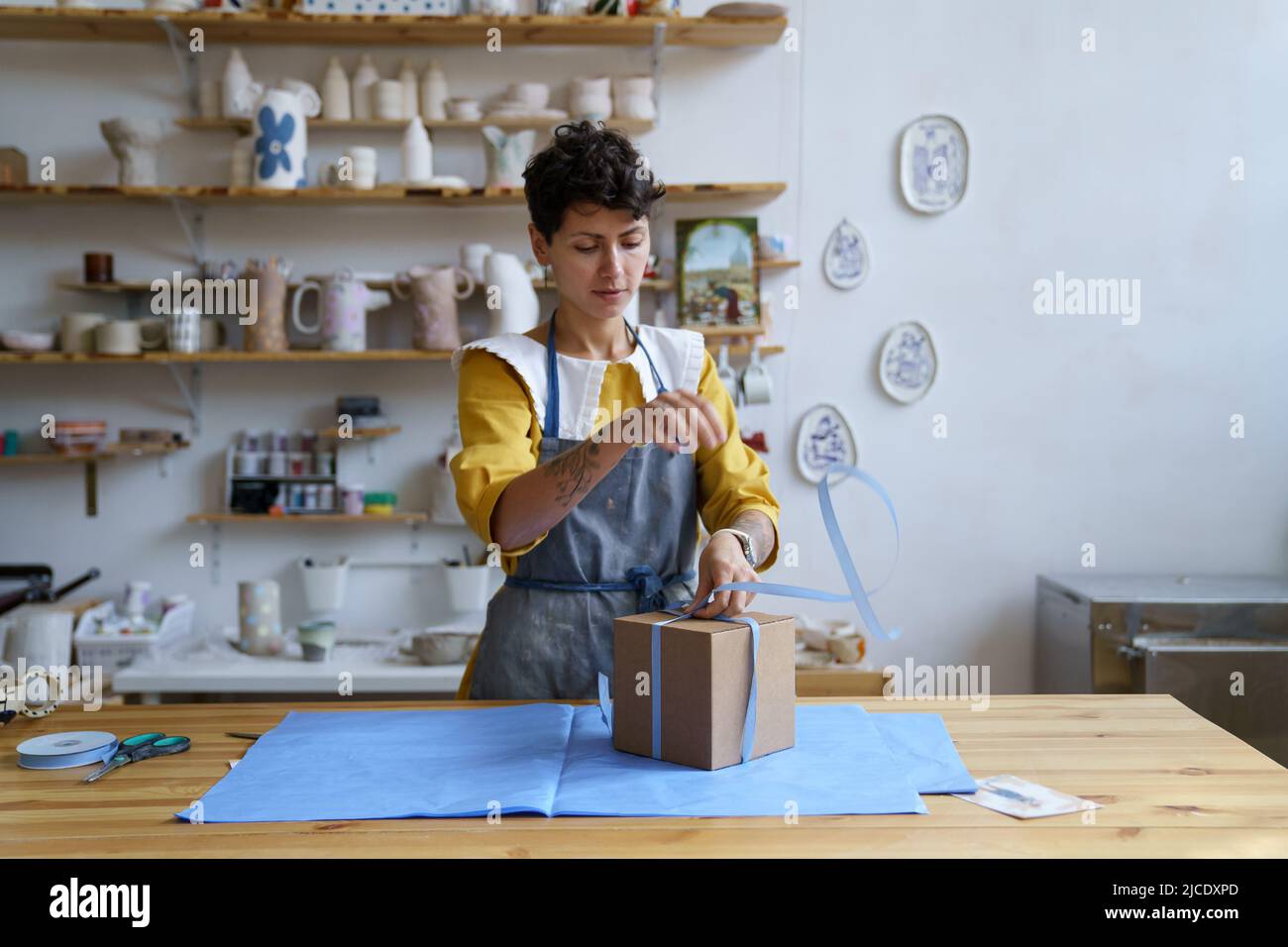 Woman pottery shop owner packing order in studio for shipping, ceramist ...