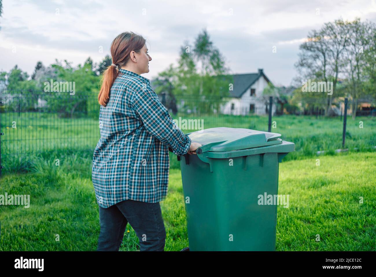 European 20s girl take out the trash can sorting garbage near a home ...