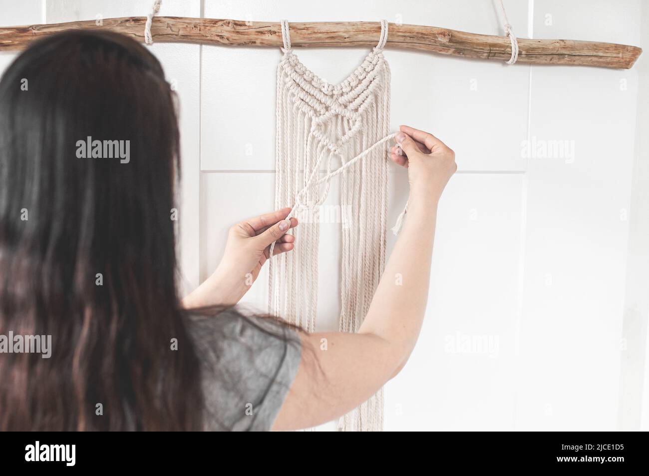 girl weaves a macrame pattern from natural white cotton threads for a ...