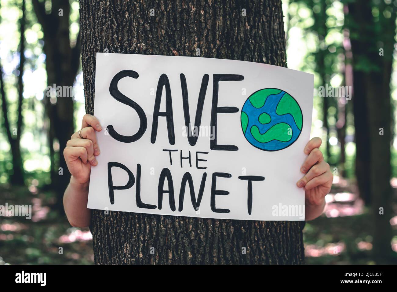 Poster in the call to save the planet in female hands in the forest Stock Photo - Alamy
