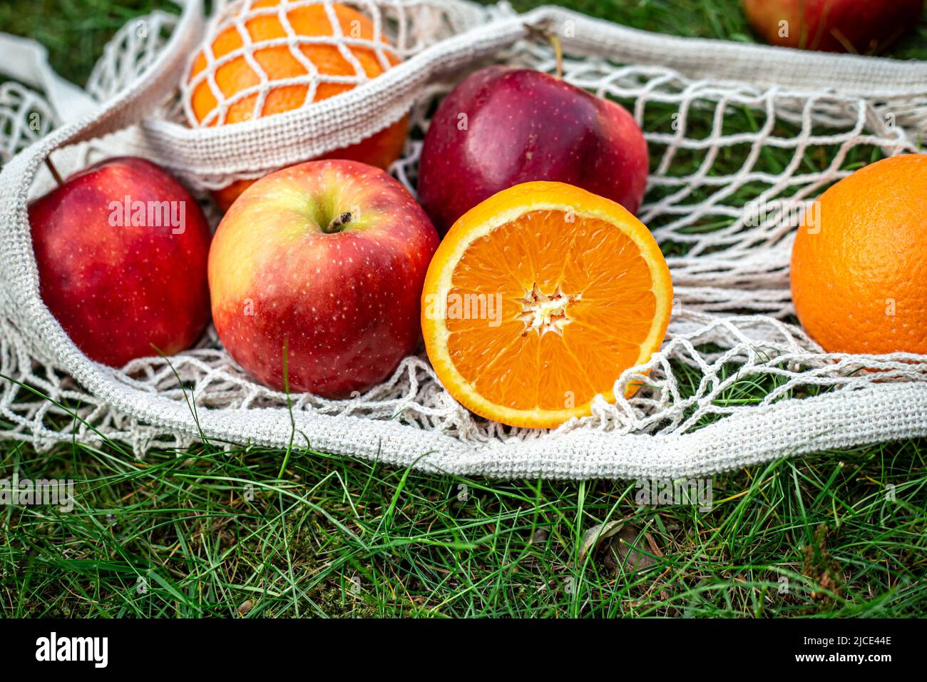Bright fruits in a white string bag in the grass Stock Photo - Alamy