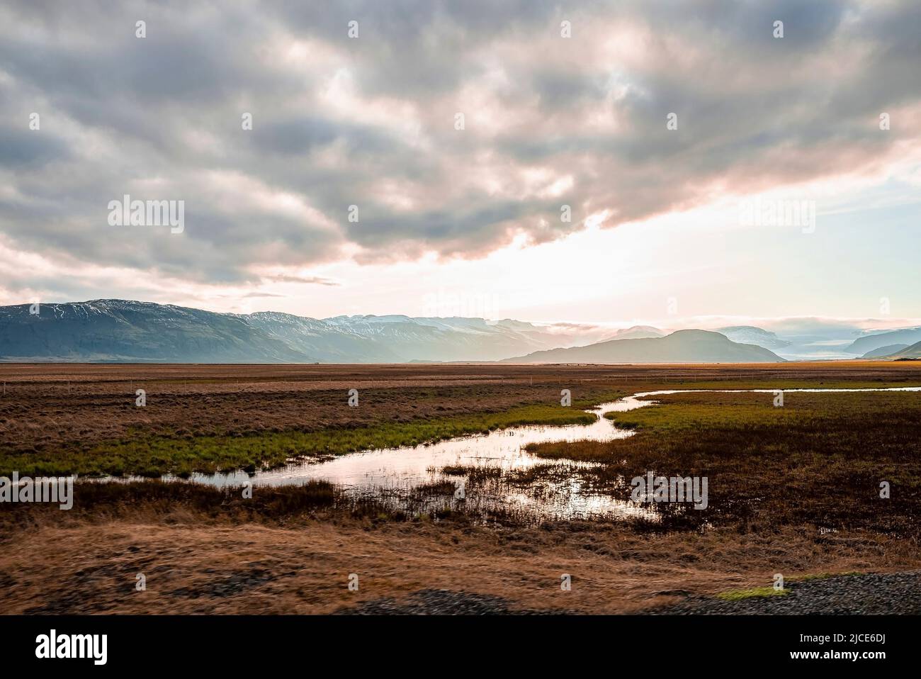 View of stream flowing amidst grassy field in volcanic valley against ...