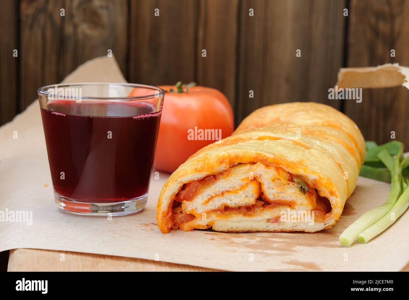 Pizza stromboli cut with glass of red wine, fresh scallion and tomato ...