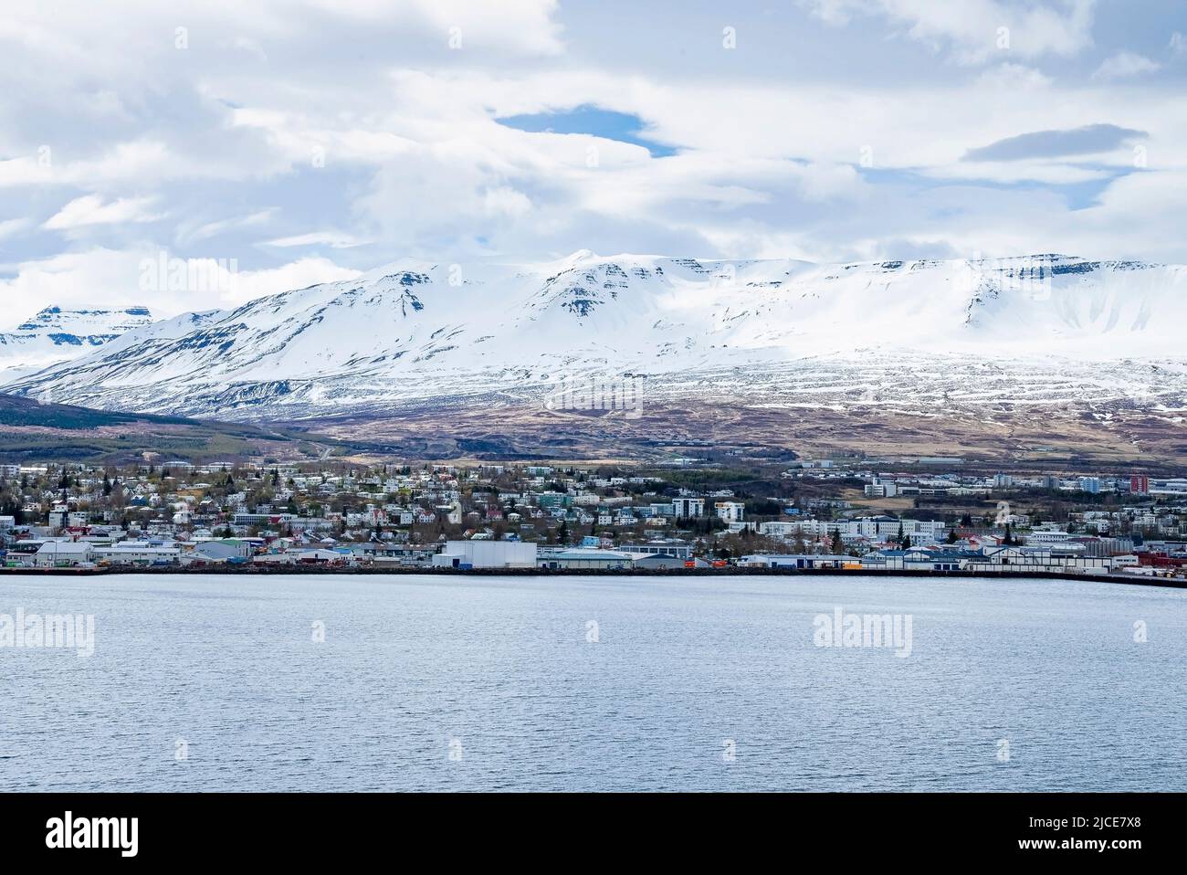 Scenic view of cityscape at seashore with snowcapped mountains in ...