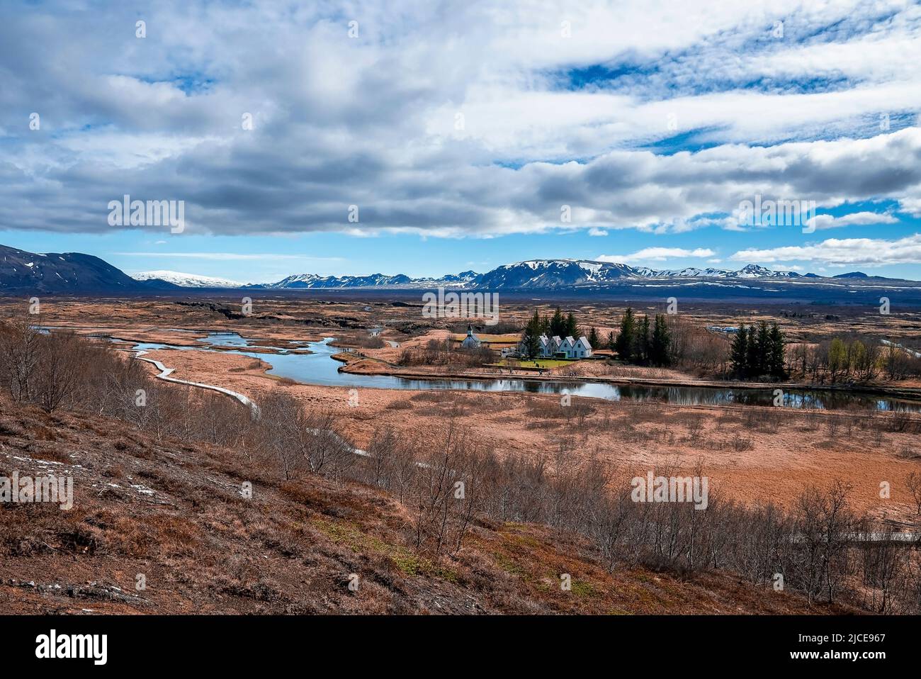 Distant view of houses amidst stream and dramatic landscape against ...