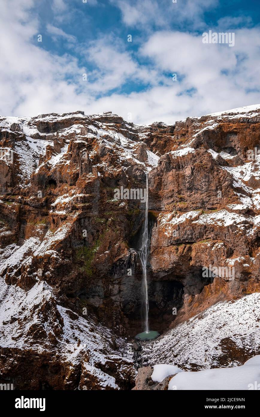 View of small waterfall falling from snow covered mountains against ...