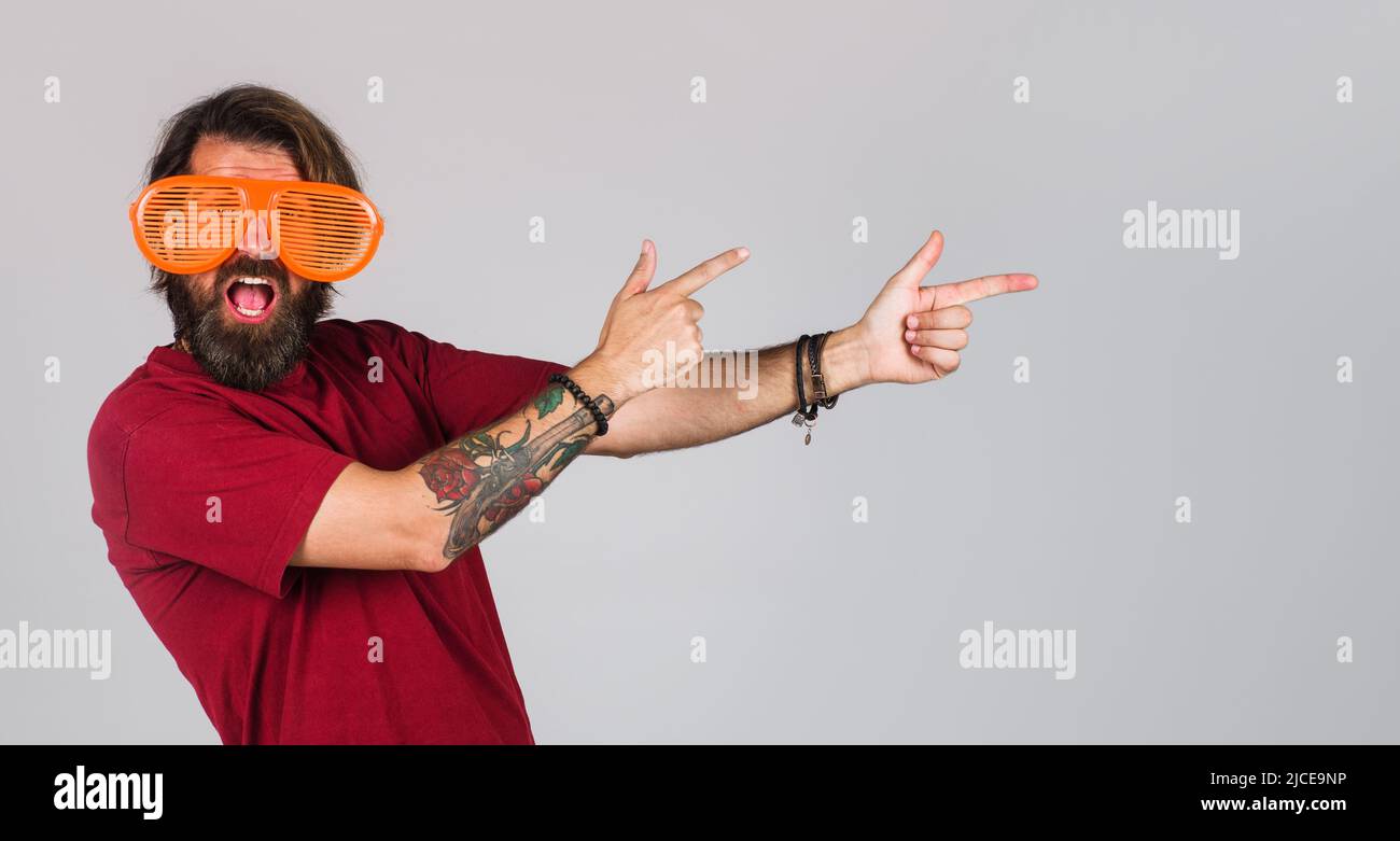 Bearded man pointing fingers to empty space. Funny guy in big glasses ...