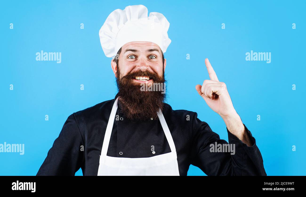 Bearded male chef, cook or baker in uniform, apron and chefs hat point ...