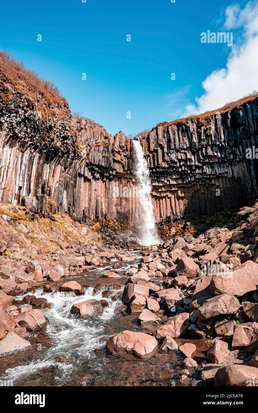 Beautiful cascades of Svartifoss waterfall and flowing stream against ...
