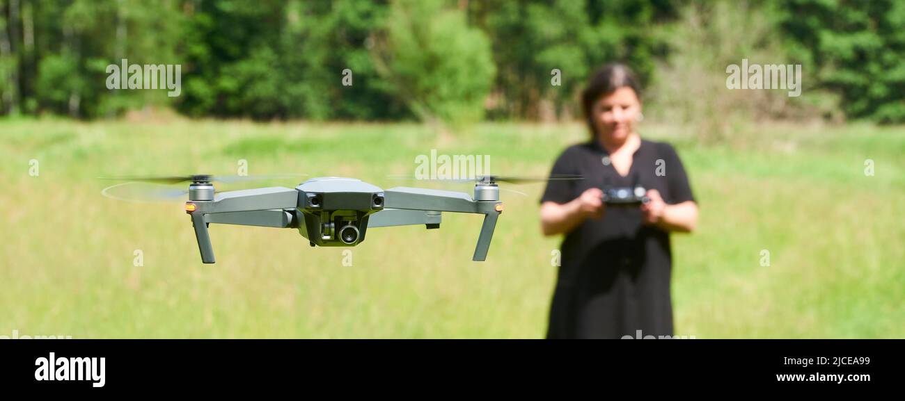 Young smiling woman pilot operating the drone by remote control. Flying ...