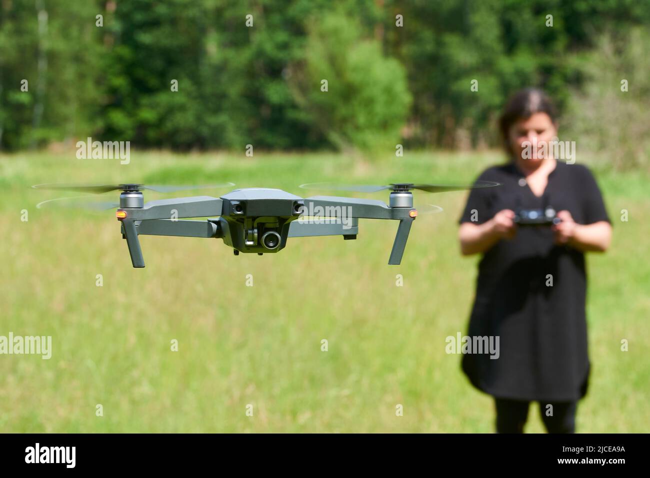 Young smiling woman pilot operating the drone by remote control. Flying ...