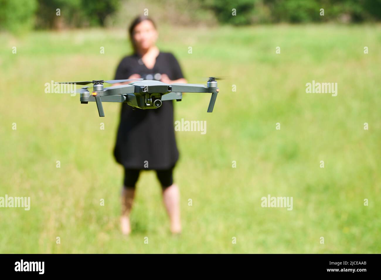 Young smiling woman pilot operating the drone by remote control. Flying ...