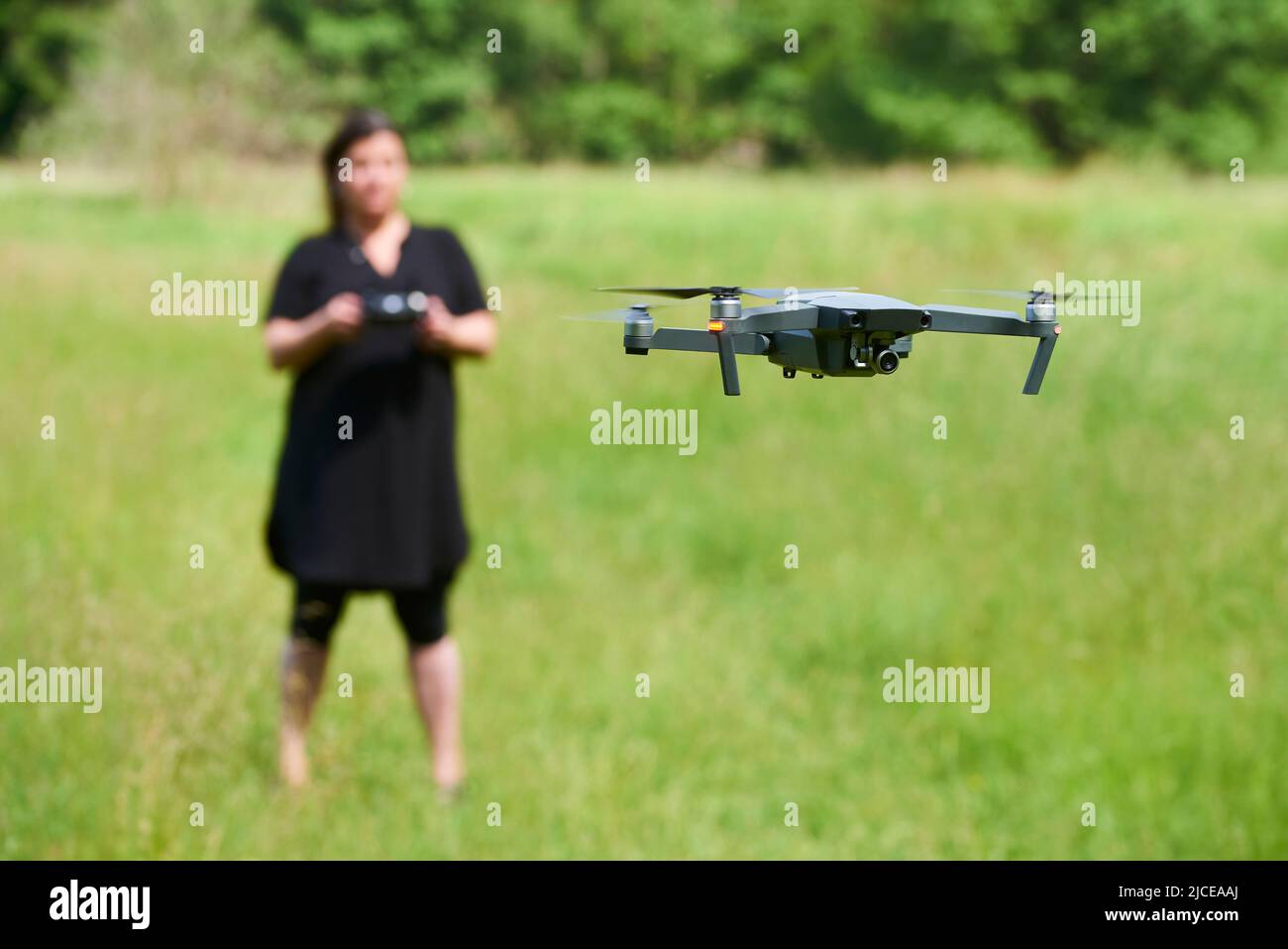 Young smiling woman pilot operating the drone by remote control. Flying ...